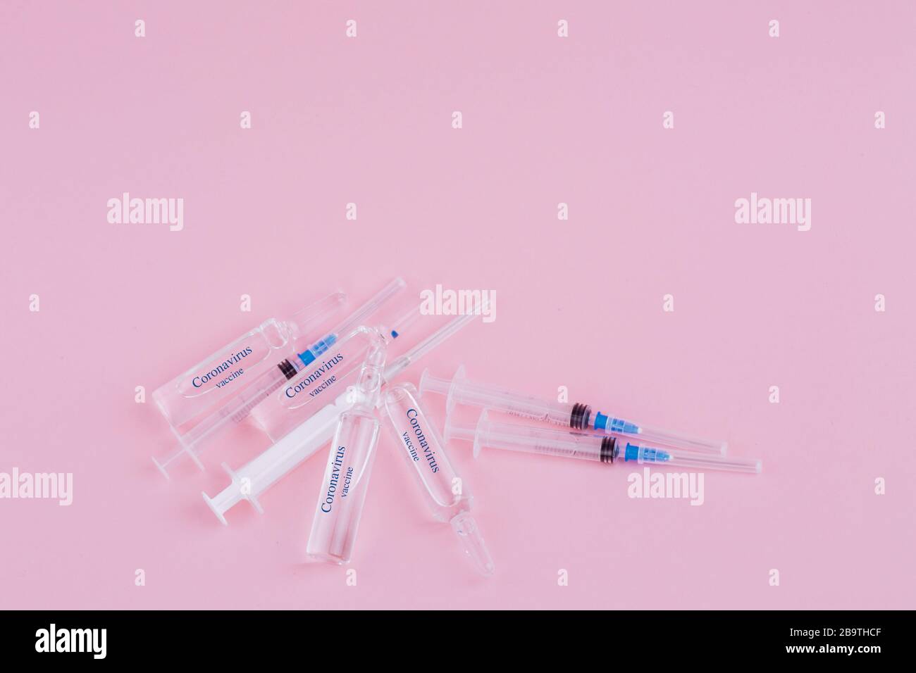 Plastic medical syringe with injection needles and ampoules on a pink ...