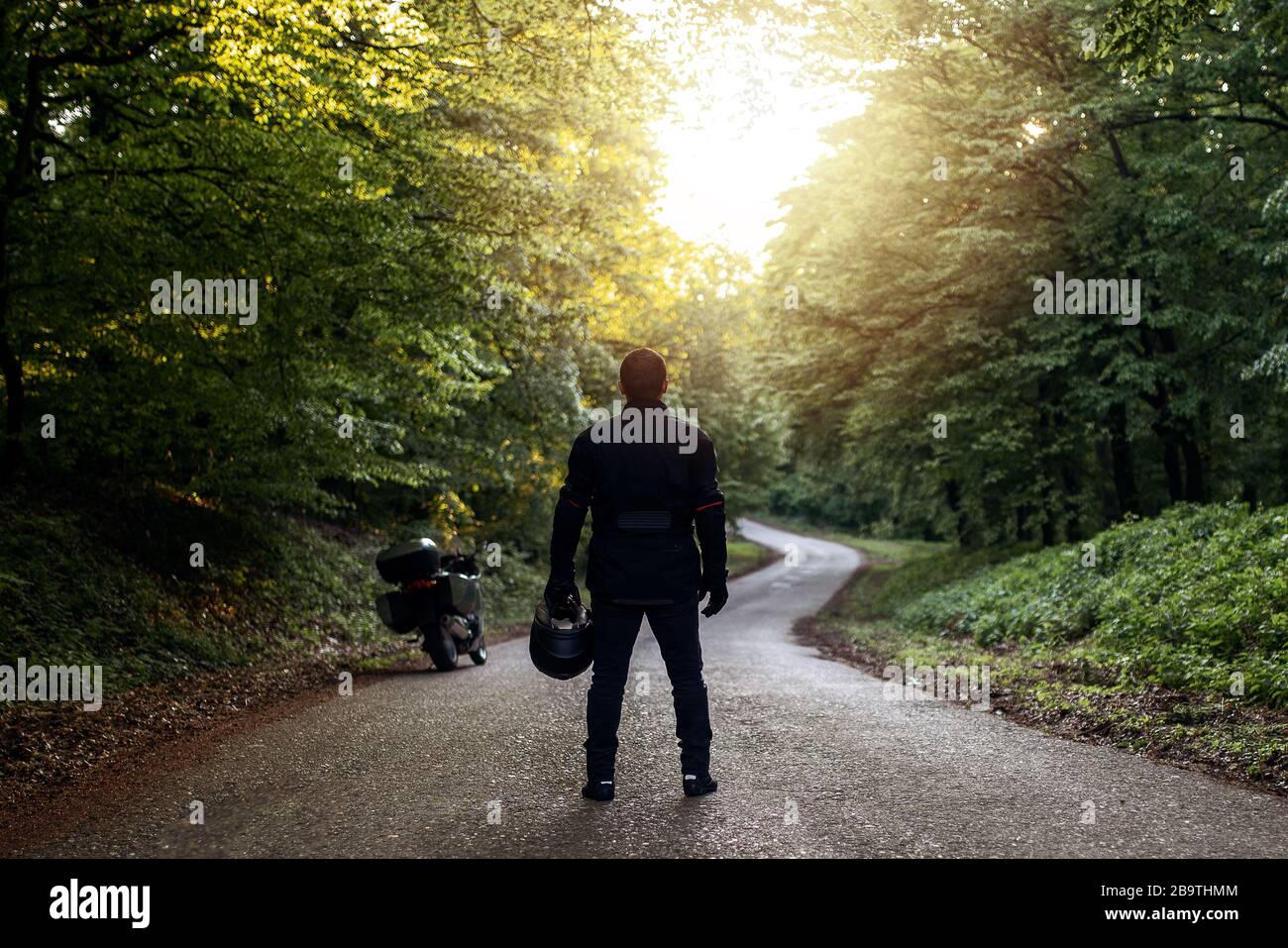 Motorcycle guy in raiders clothes, gearing up. A young men stands near ...