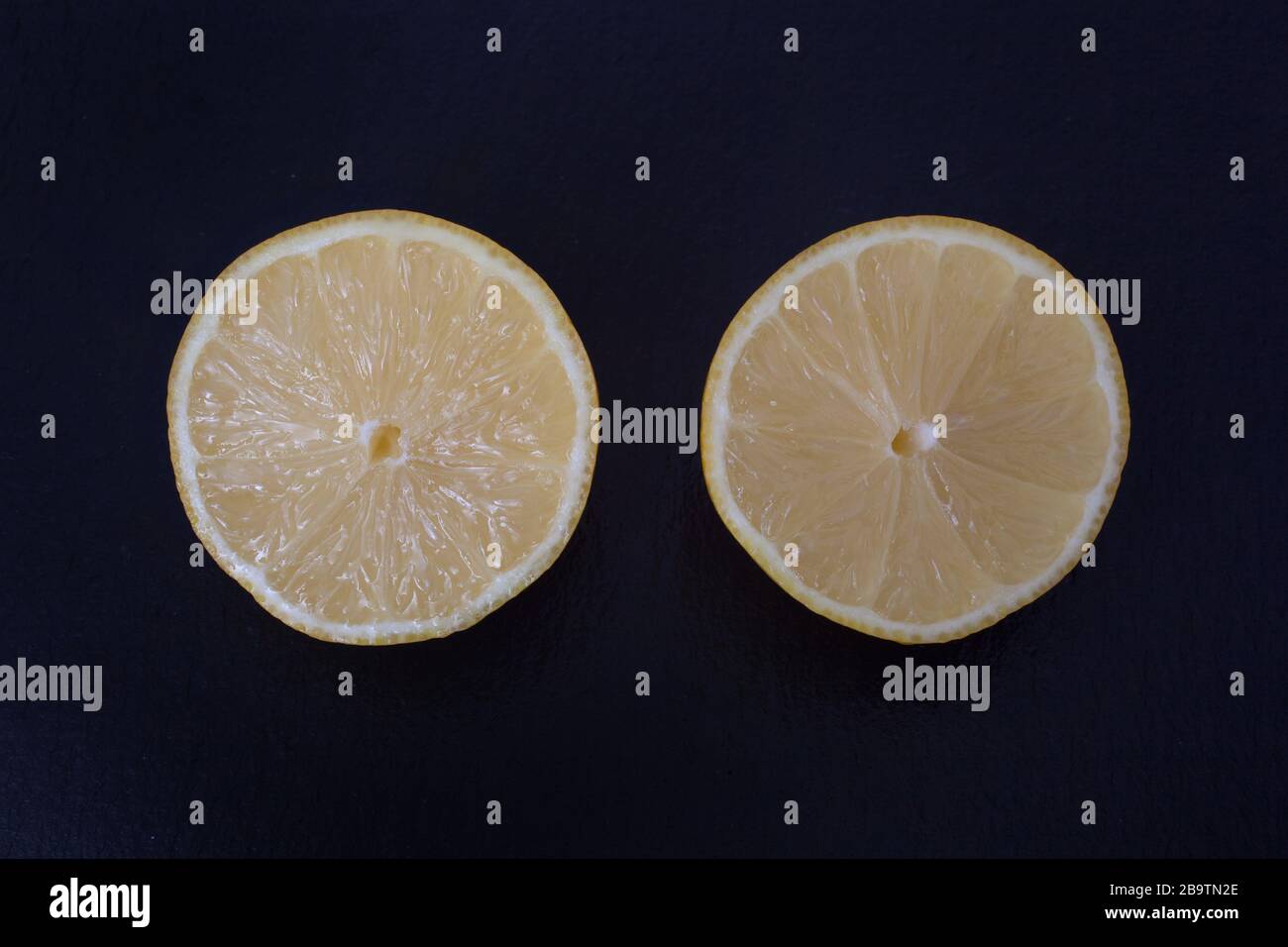 Two lemon halves against a black background Stock Photo - Alamy