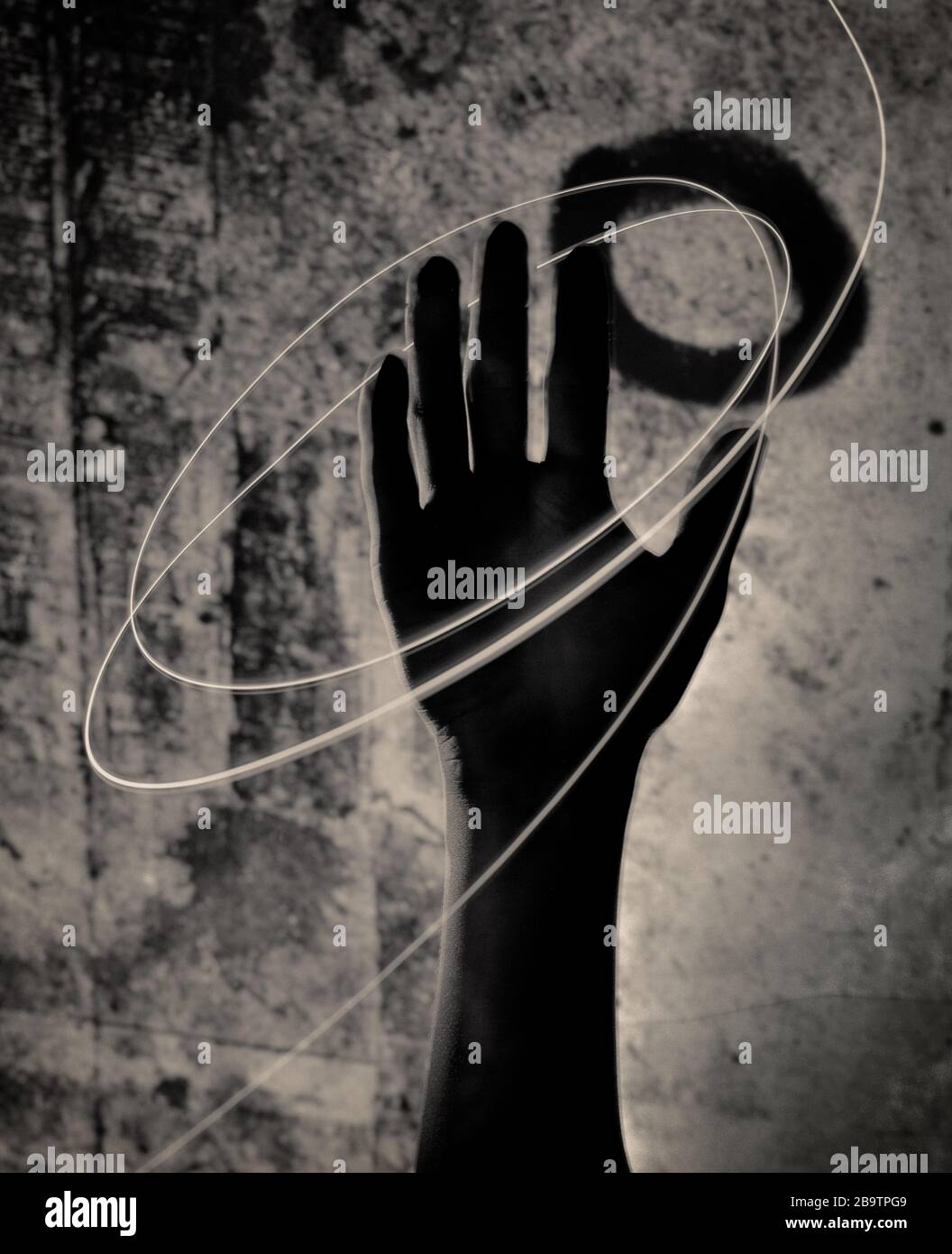black and white hand reaching for circle surrounded by light swirl ...