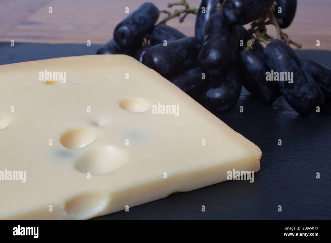 Norwegian Jarlsberg cheese with long black grapes Stock Photo - Alamy