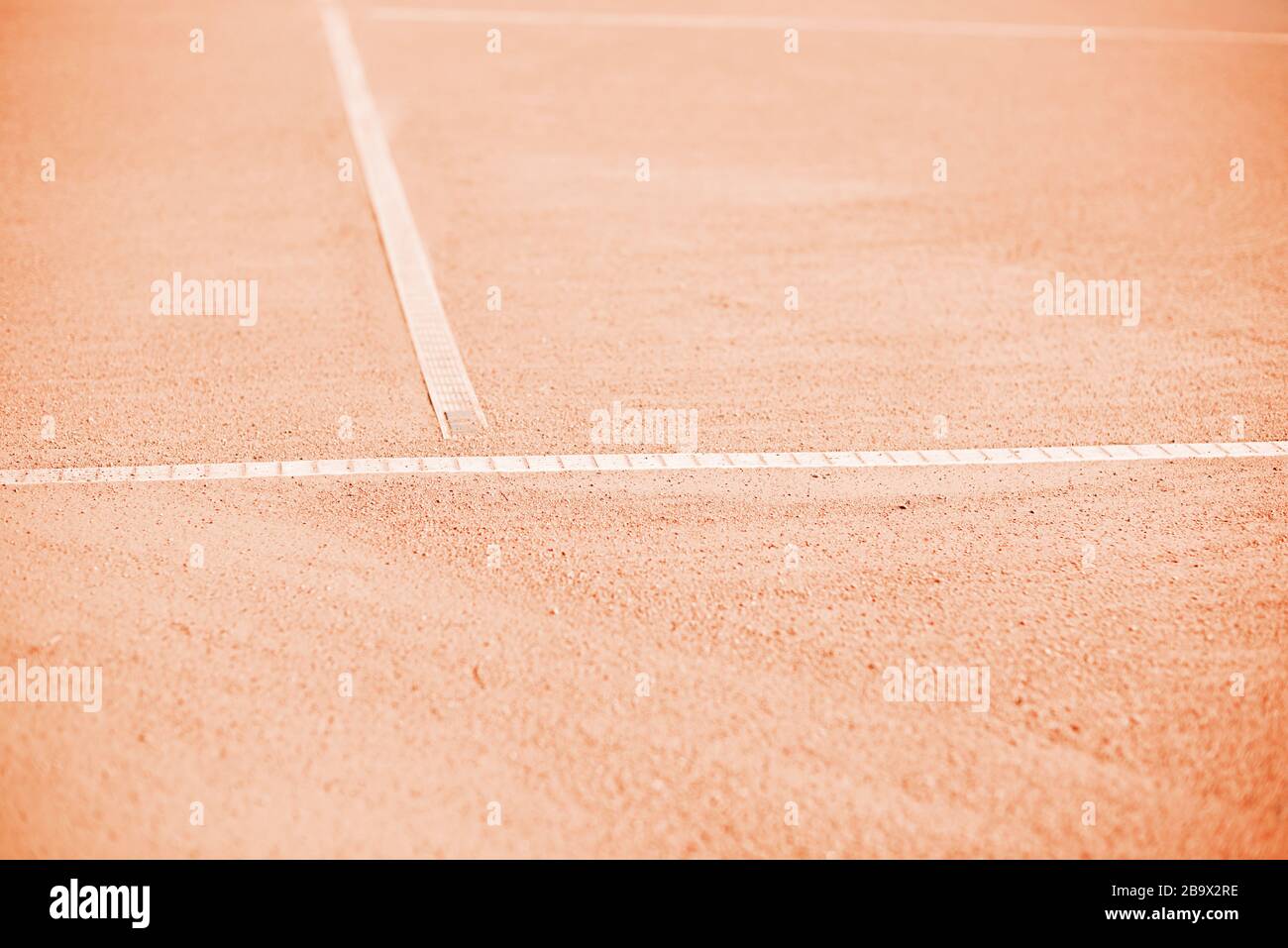 Sand and gravel tennis court sub-base. Blurred background. Coral tones ...