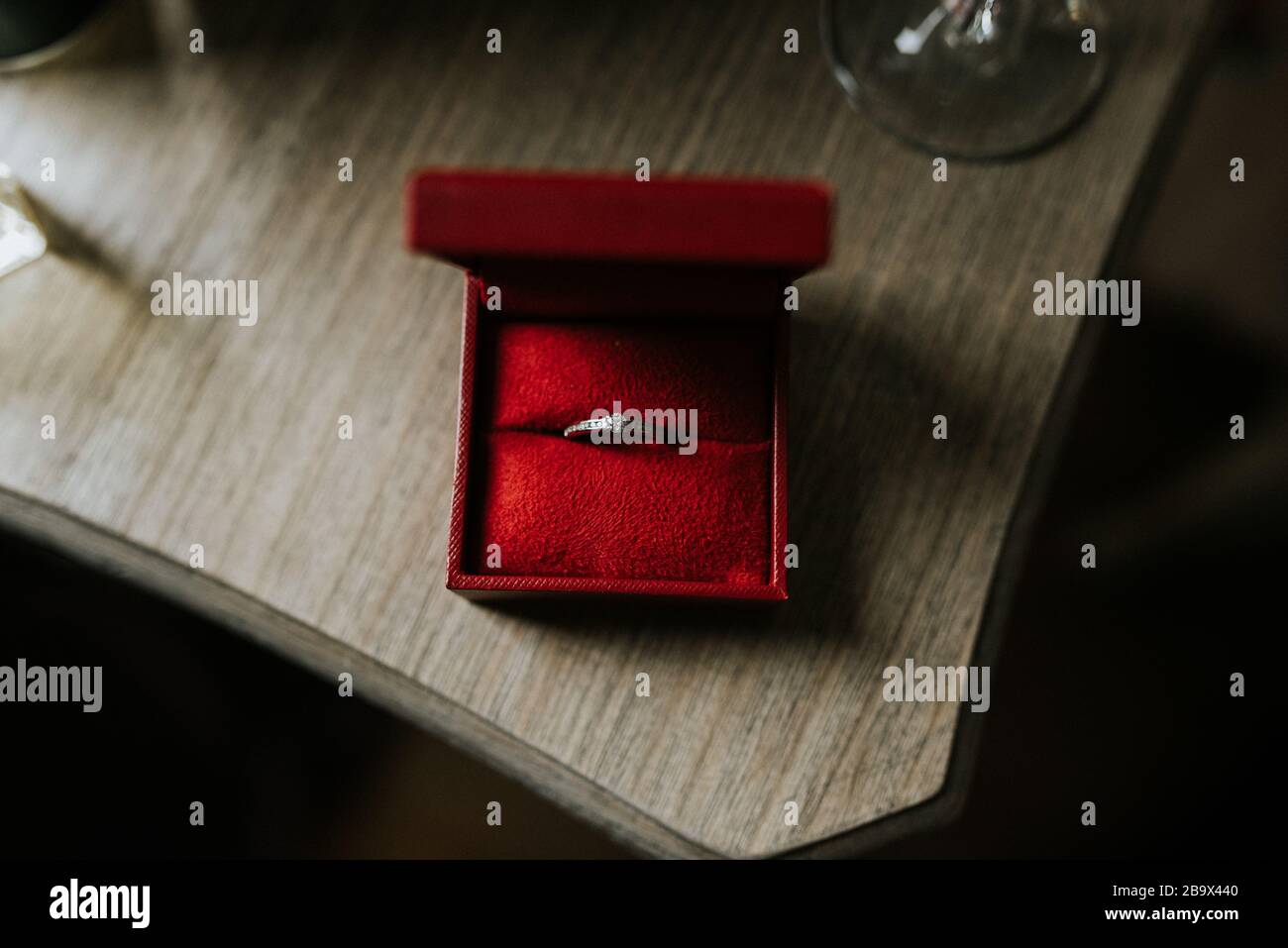 Overhead closeup shot of a wedding ring in a red box on a wooden table ...