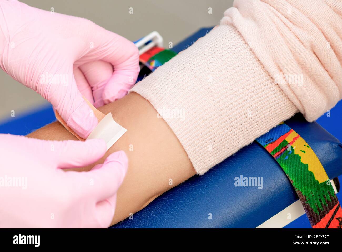Doctor in rubber protective gloves glues an adhesive plaster on arm ...
