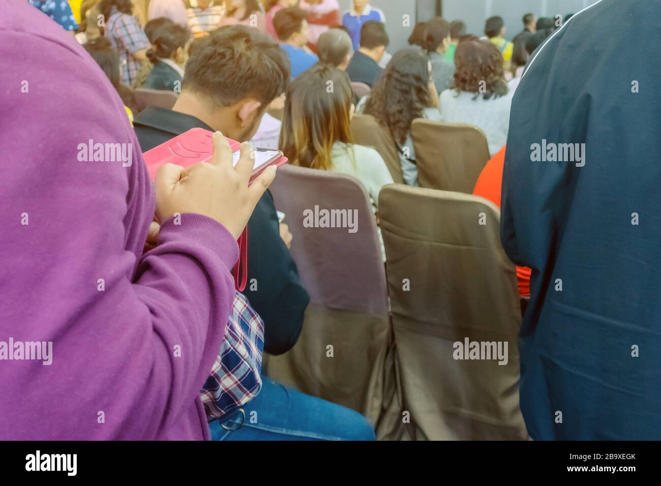 Backside view of spectators standing in a gathering in the back of ...