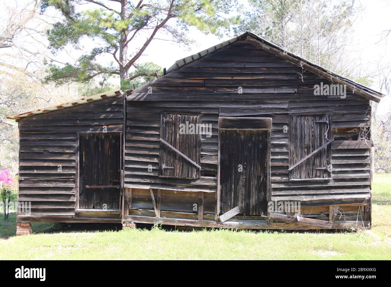 an old abandoned southern style farm barn on a sunny day with shadows ...