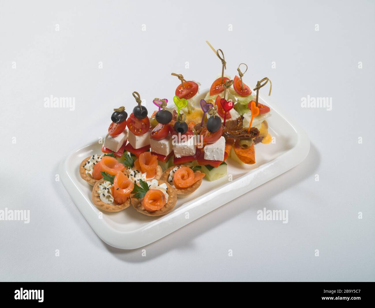 Set of canapes of fish, vegetables, meat on a plate on a white ...