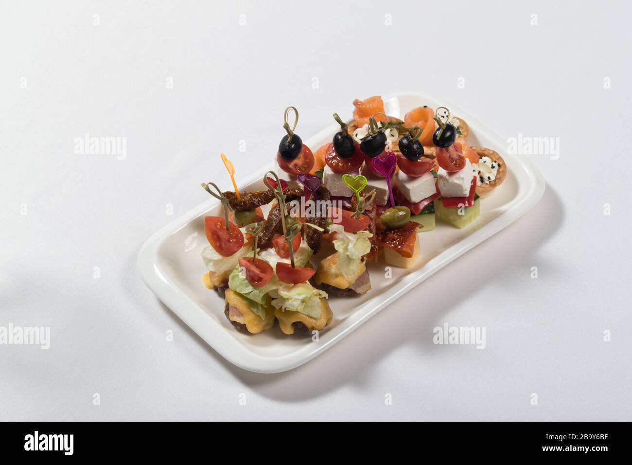 Set of canapes of fish, vegetables, meat on a plate on a white ...
