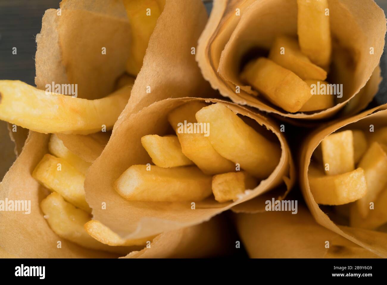 Golden slices of french fries wrapped in parchment paper. Fast food ...