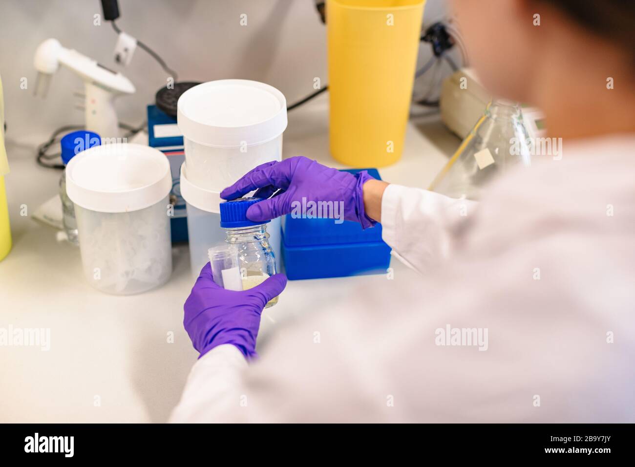 Scientist holding flask in front experiment boxes Stock Photo - Alamy