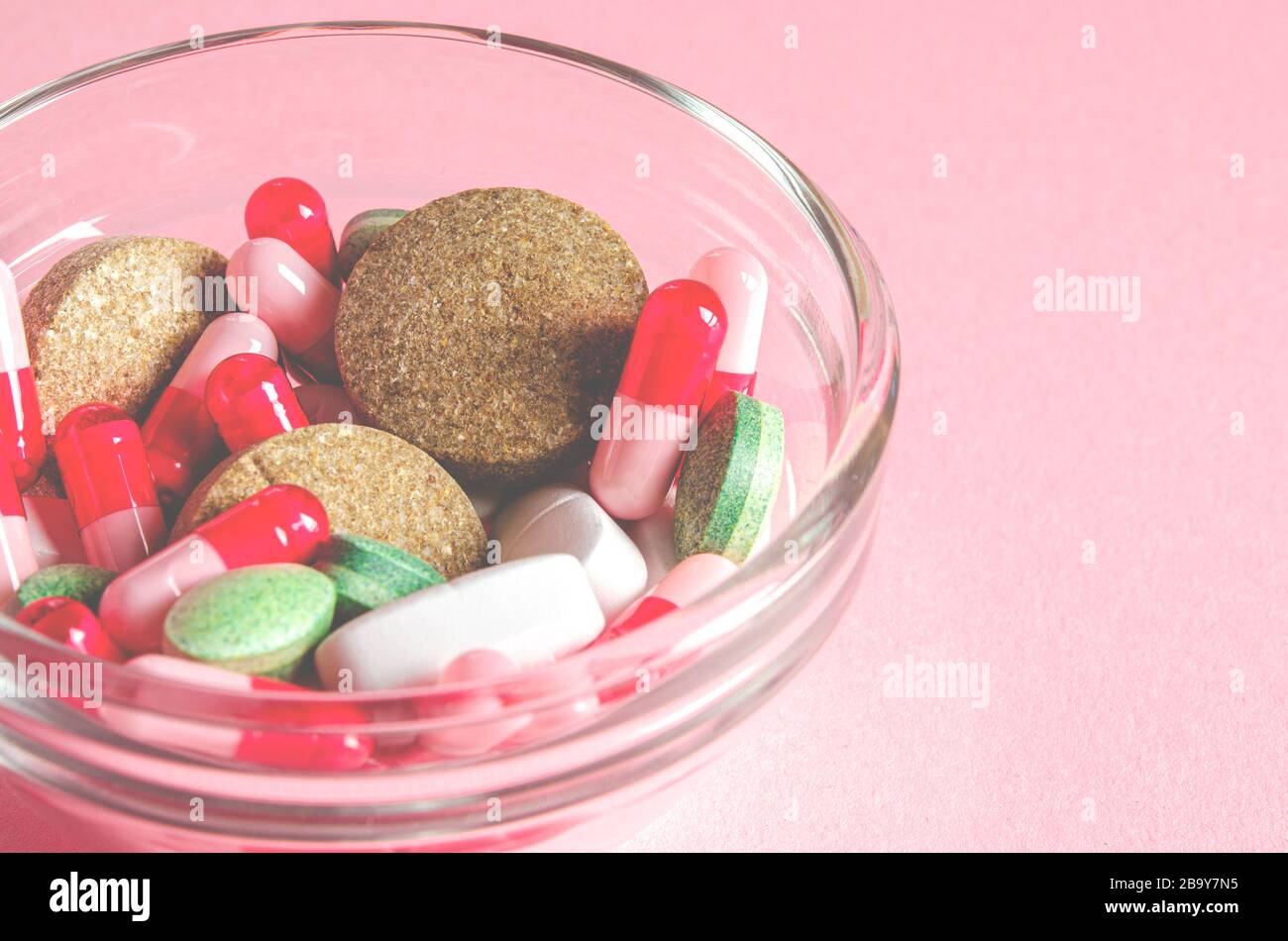 Multi-colored anti-virus tablets of different shapes lie in a glass ...