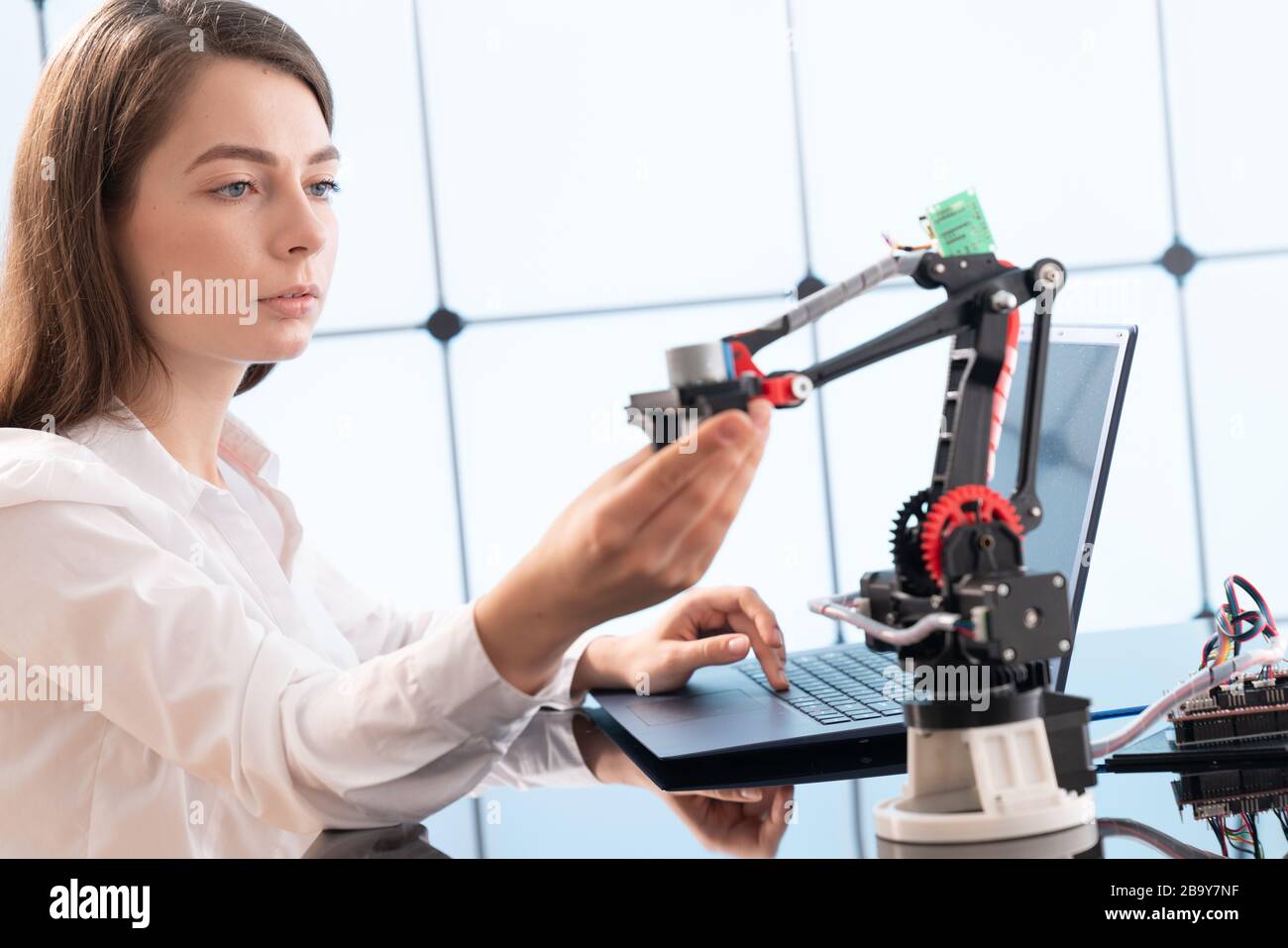 A young woman writes an algorithm for the robot arm. Science Research ...
