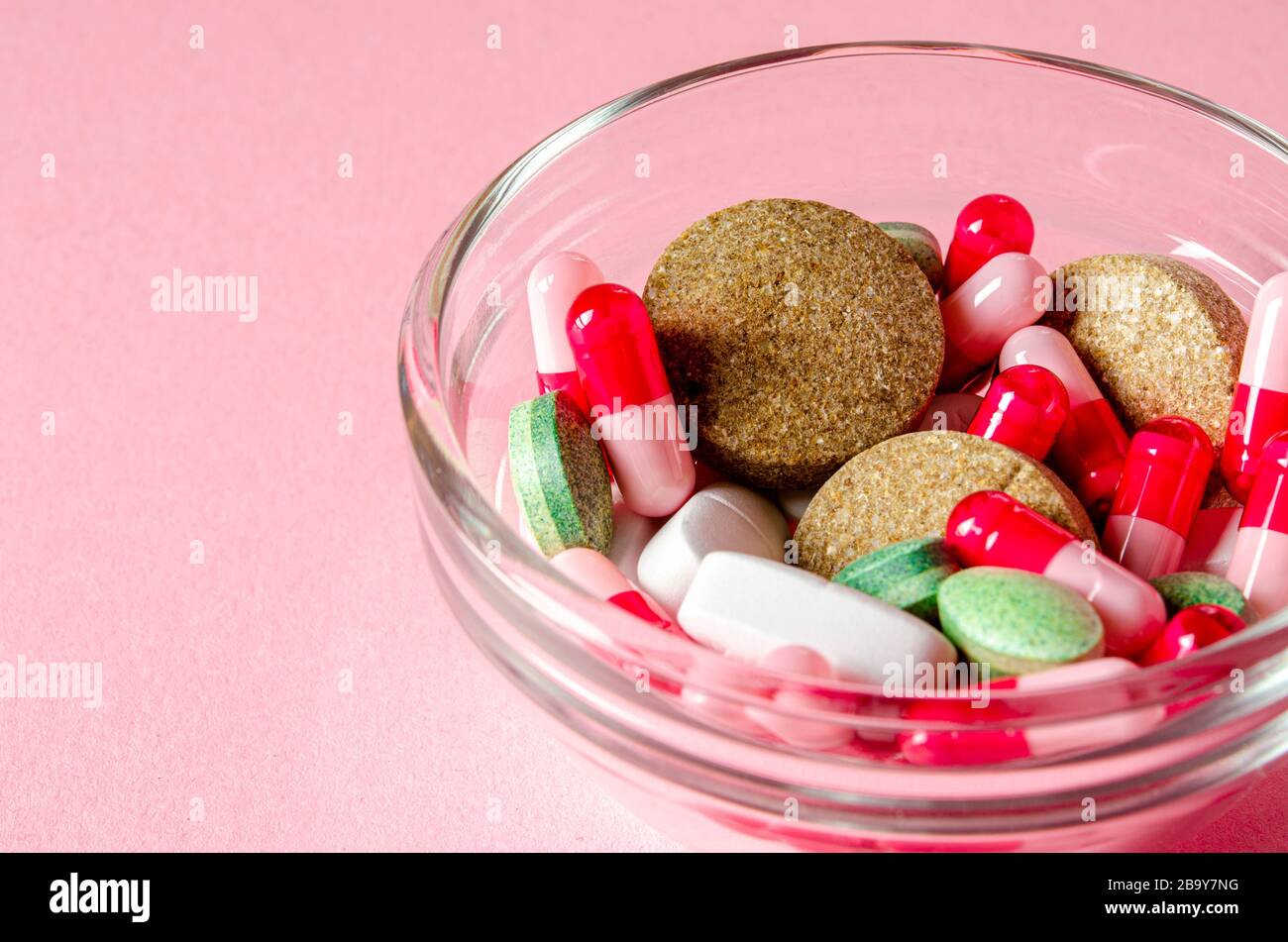 Multi-colored anti-virus tablets of different shapes lie in a glass ...