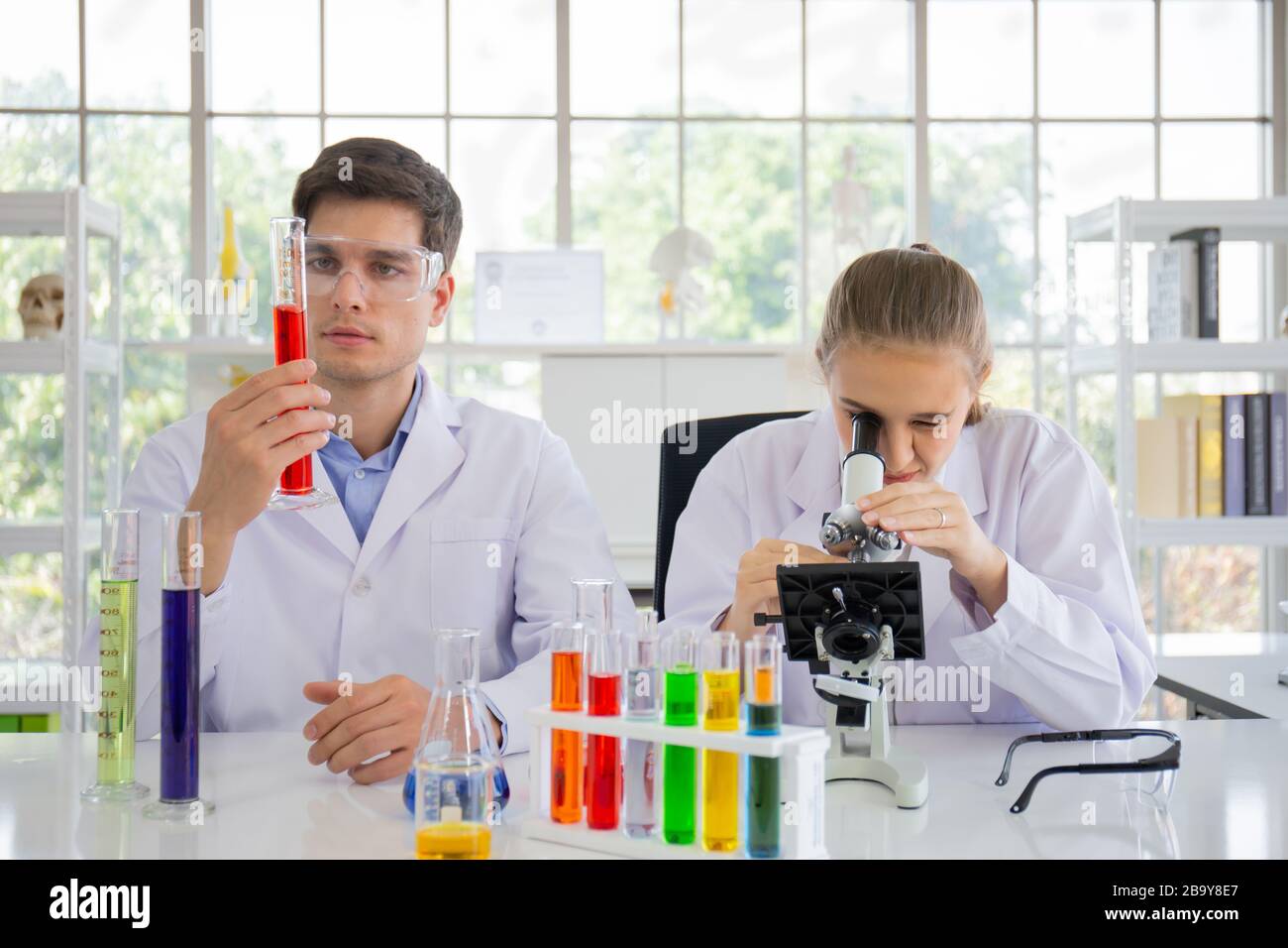 Male and female scientists working in a science laboratory with various ...