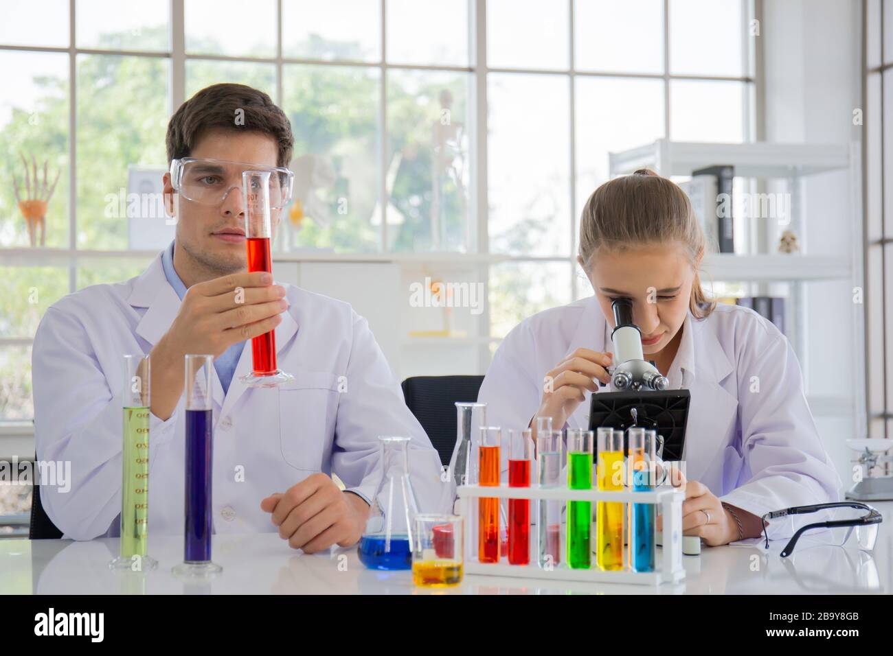 Male and female scientists working in a science laboratory with various ...