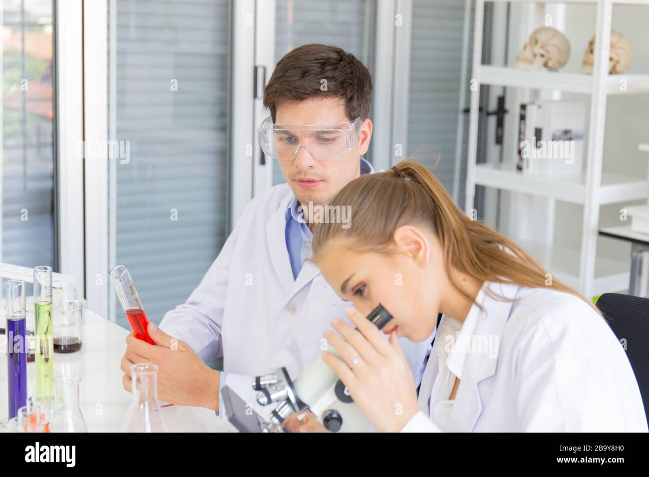Male and female scientists working in a science laboratory with various ...