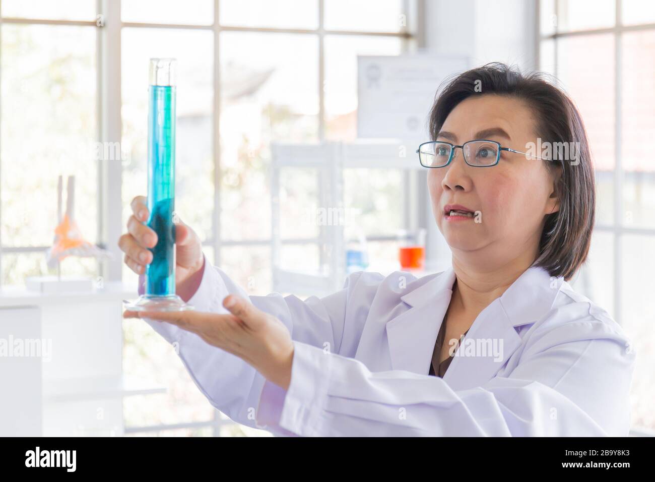 An Asian female scientist looked at the glass tube in shock Stock Photo ...