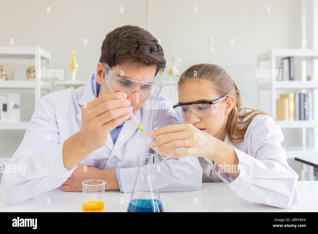 Male and female scientists working in a science laboratory with various ...