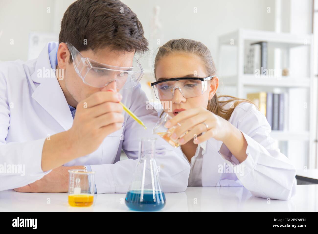 Male and female scientists working in a science laboratory with various ...