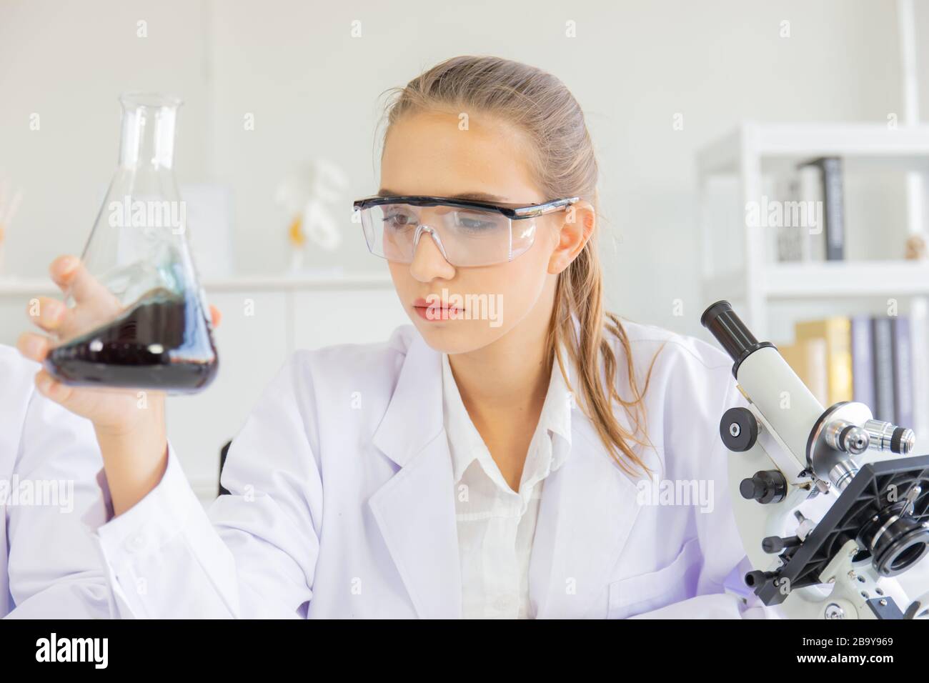 A beautiful female scientist is operating in a science lab with various ...
