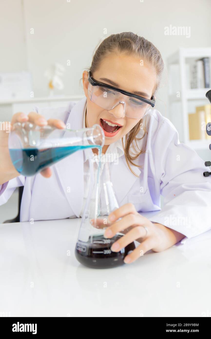 A beautiful female scientist is operating in a science lab with various ...