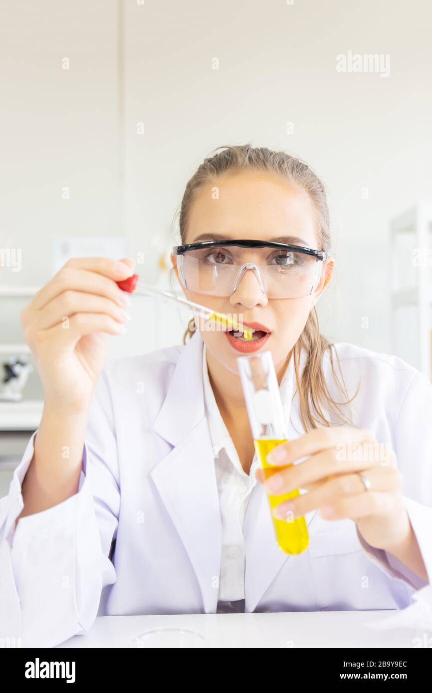 A beautiful female scientist is operating in a science lab with various ...