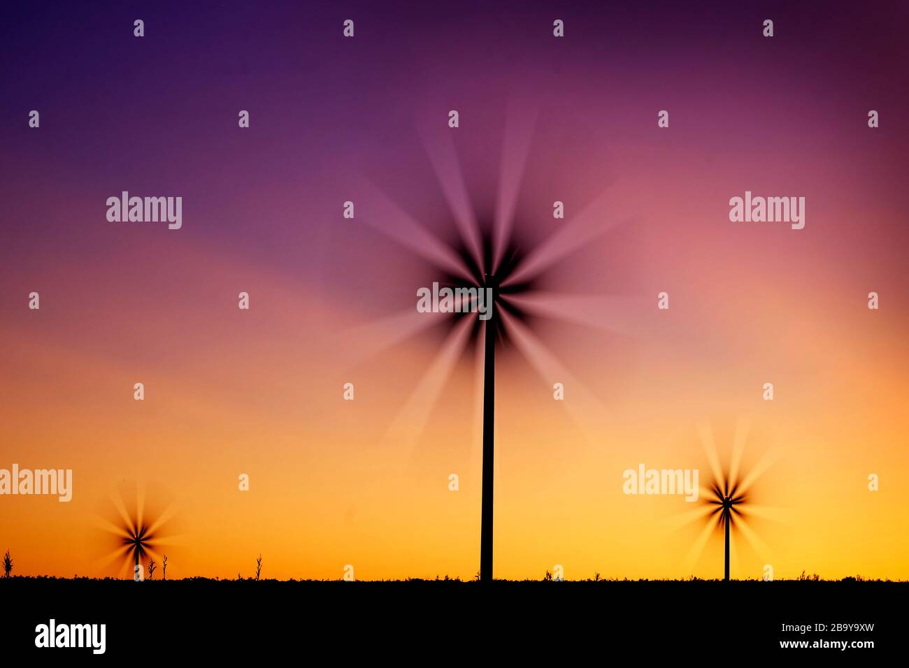 Windmill wind turbines spinning fast in wind at sunset or sunrise Stock ...