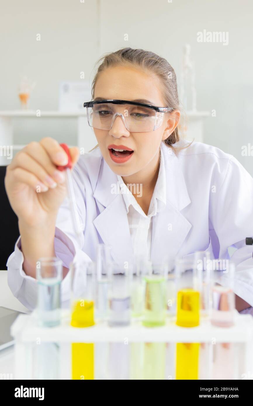 A beautiful female scientist is operating in a science lab with various ...
