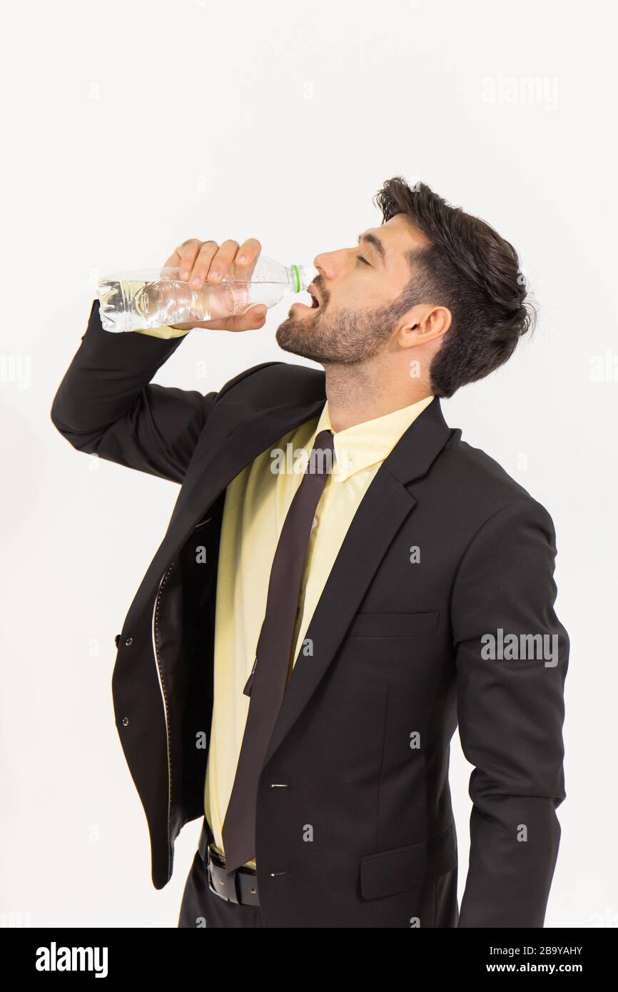 A handsome young businessman standing alone, drinking water from a ...