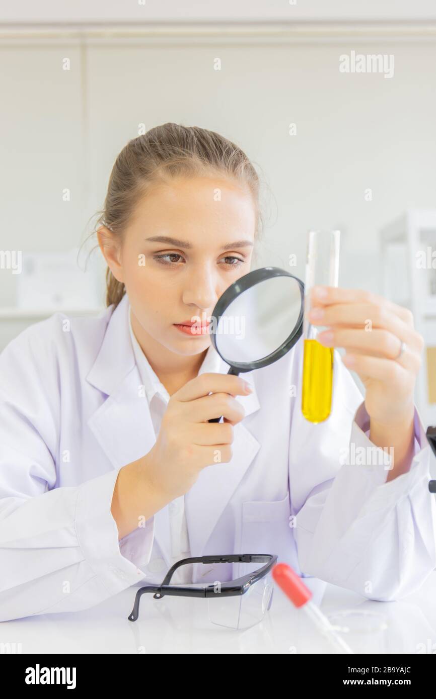 A beautiful female scientist is operating in a science lab with various ...