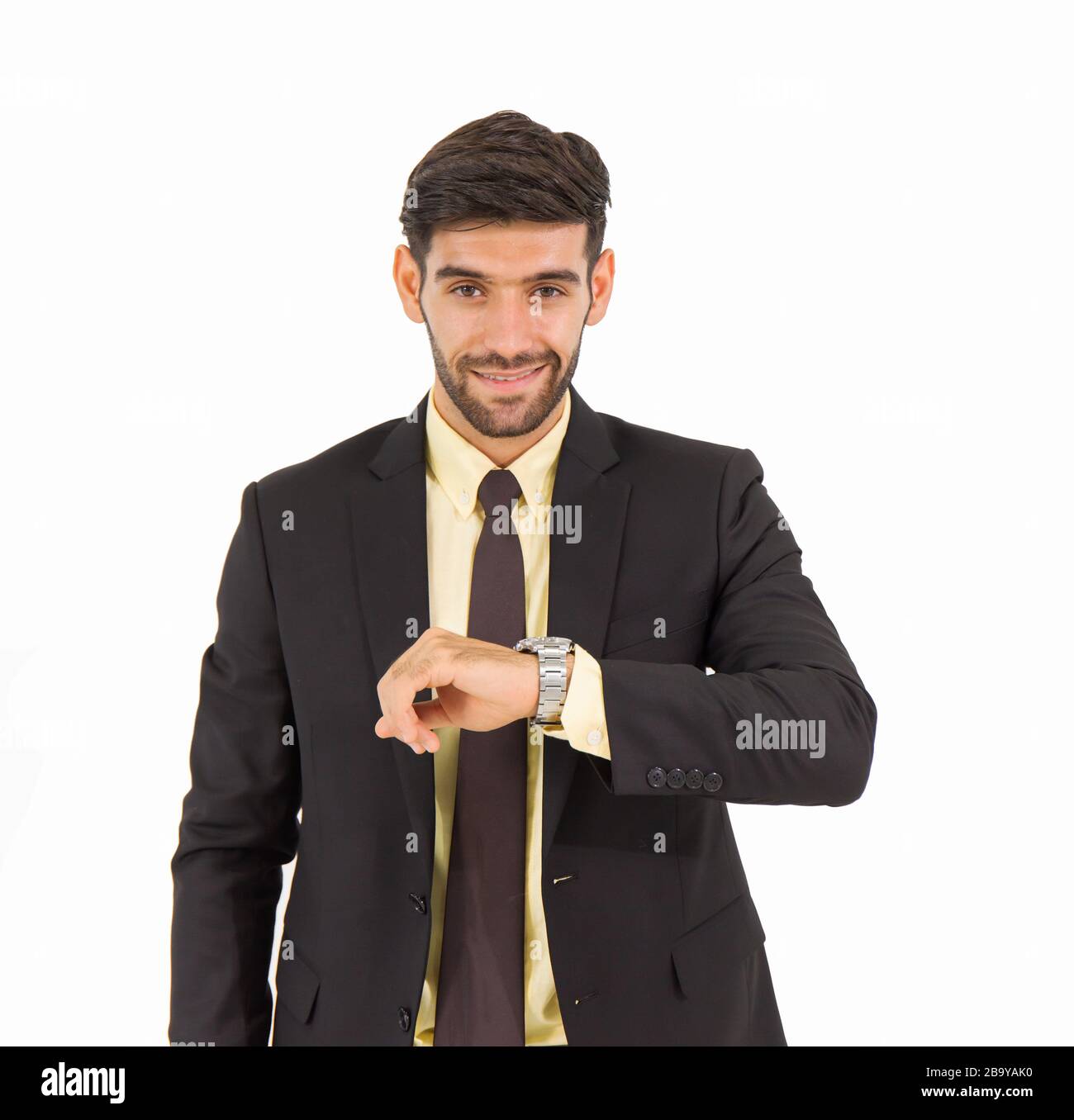 A handsome young man stood looking at his watch isolated on a white ...