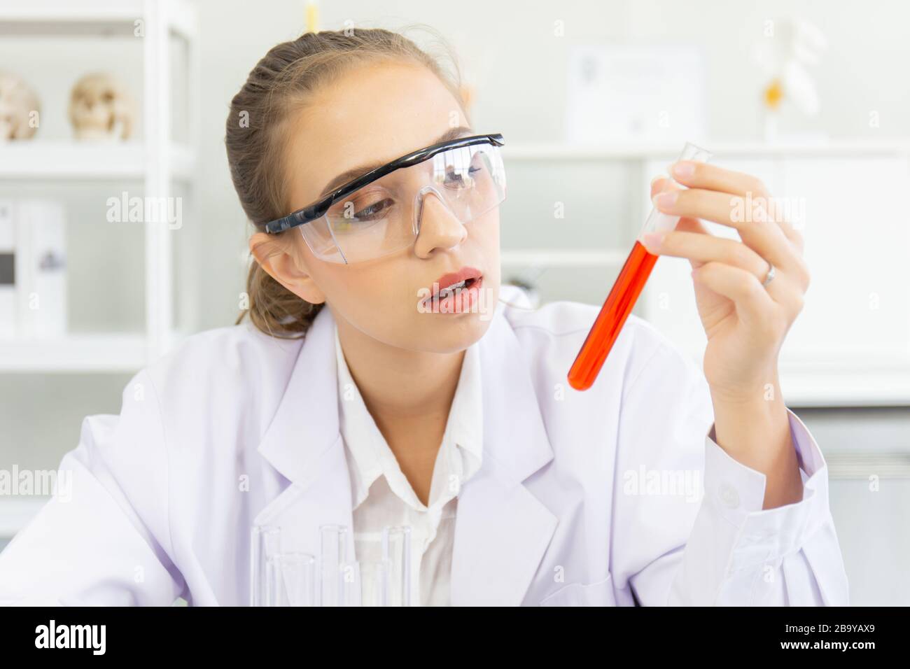 A beautiful female scientist is operating in a science lab with various ...