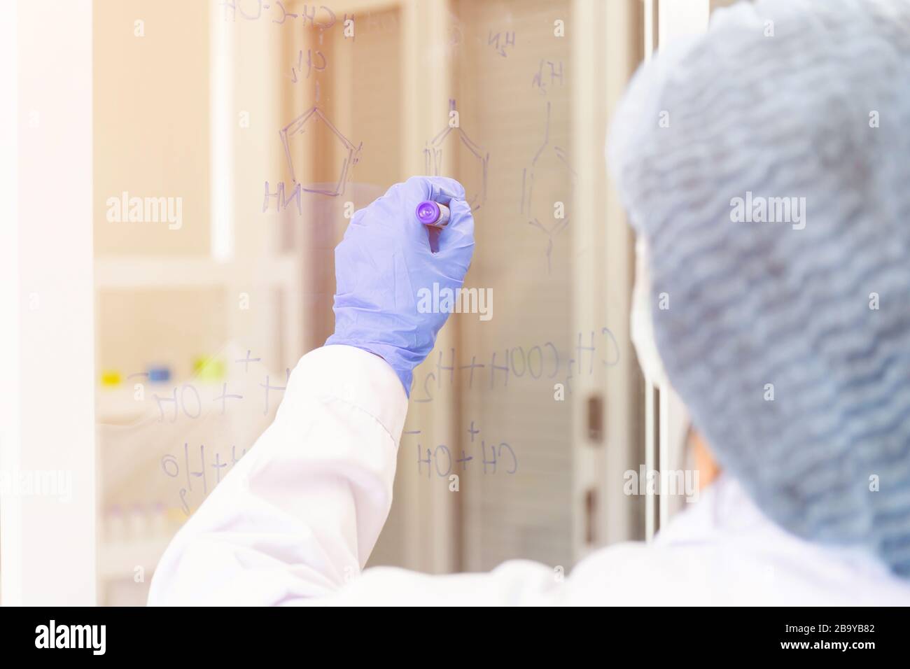 An Asian female scientist is writing down the formula for calculating ...