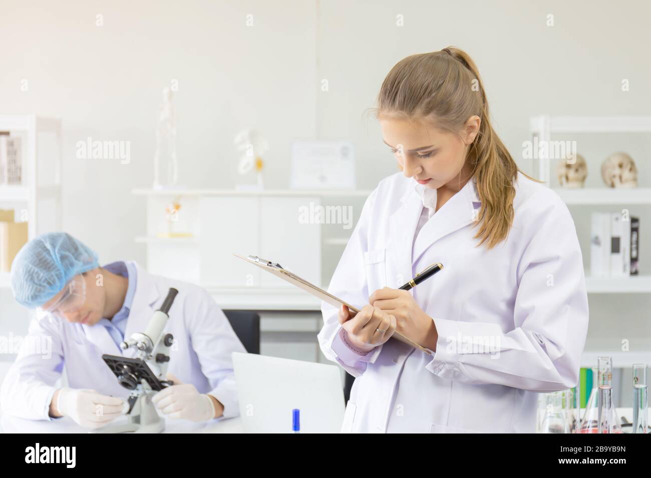 Male and female scientists working in a science laboratory with various ...