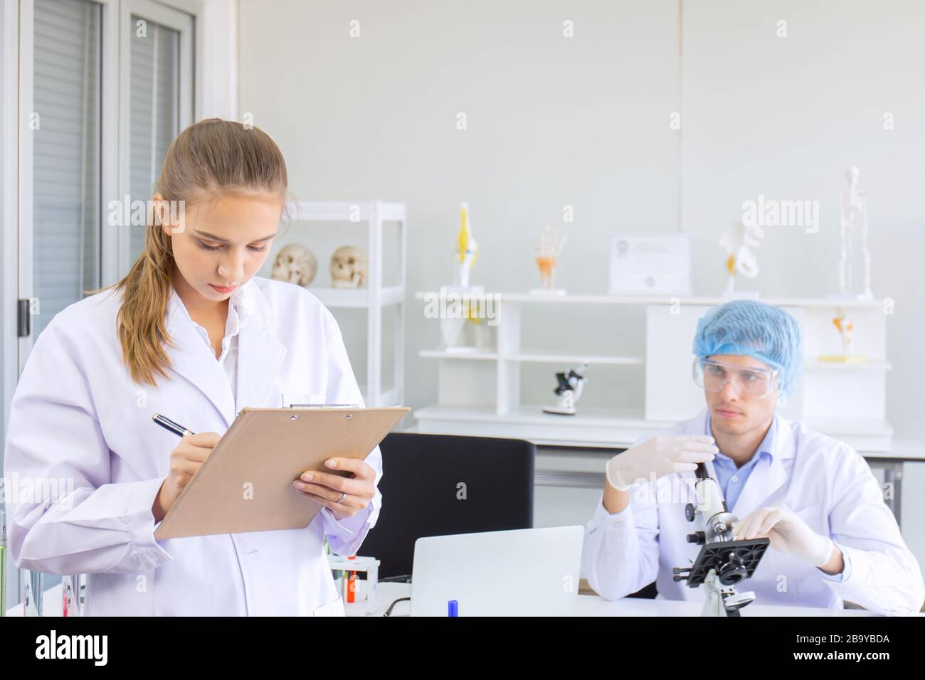 Male and female scientists working in a science laboratory with various ...