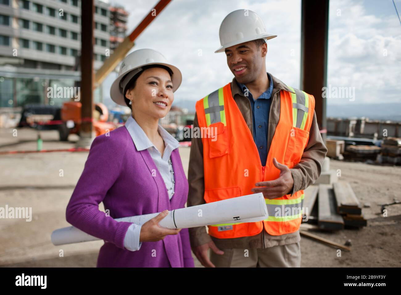 Two colleagues discussing a project on a construction site Stock Photo ...