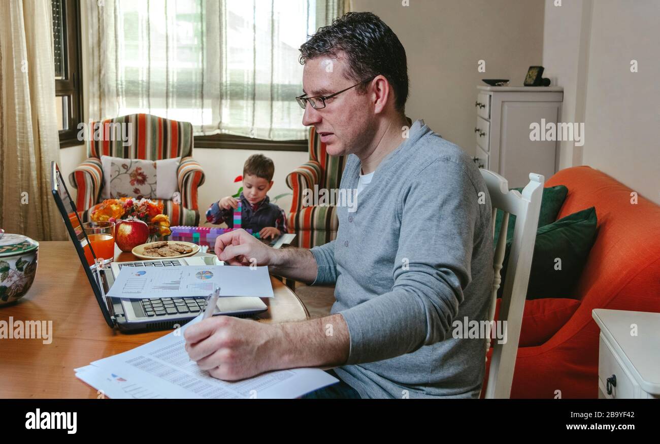 Father working at home while her son plays Stock Photo - Alamy