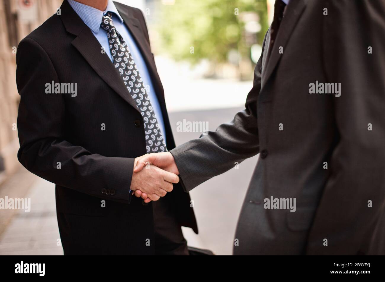 Two businessmen shake hands outside a building Stock Photo - Alamy