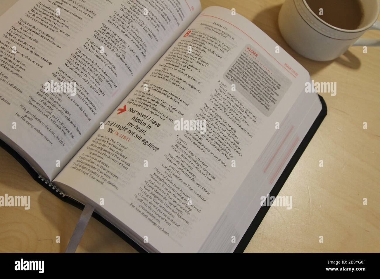 Open Bible reading on plain surface Stock Photo - Alamy