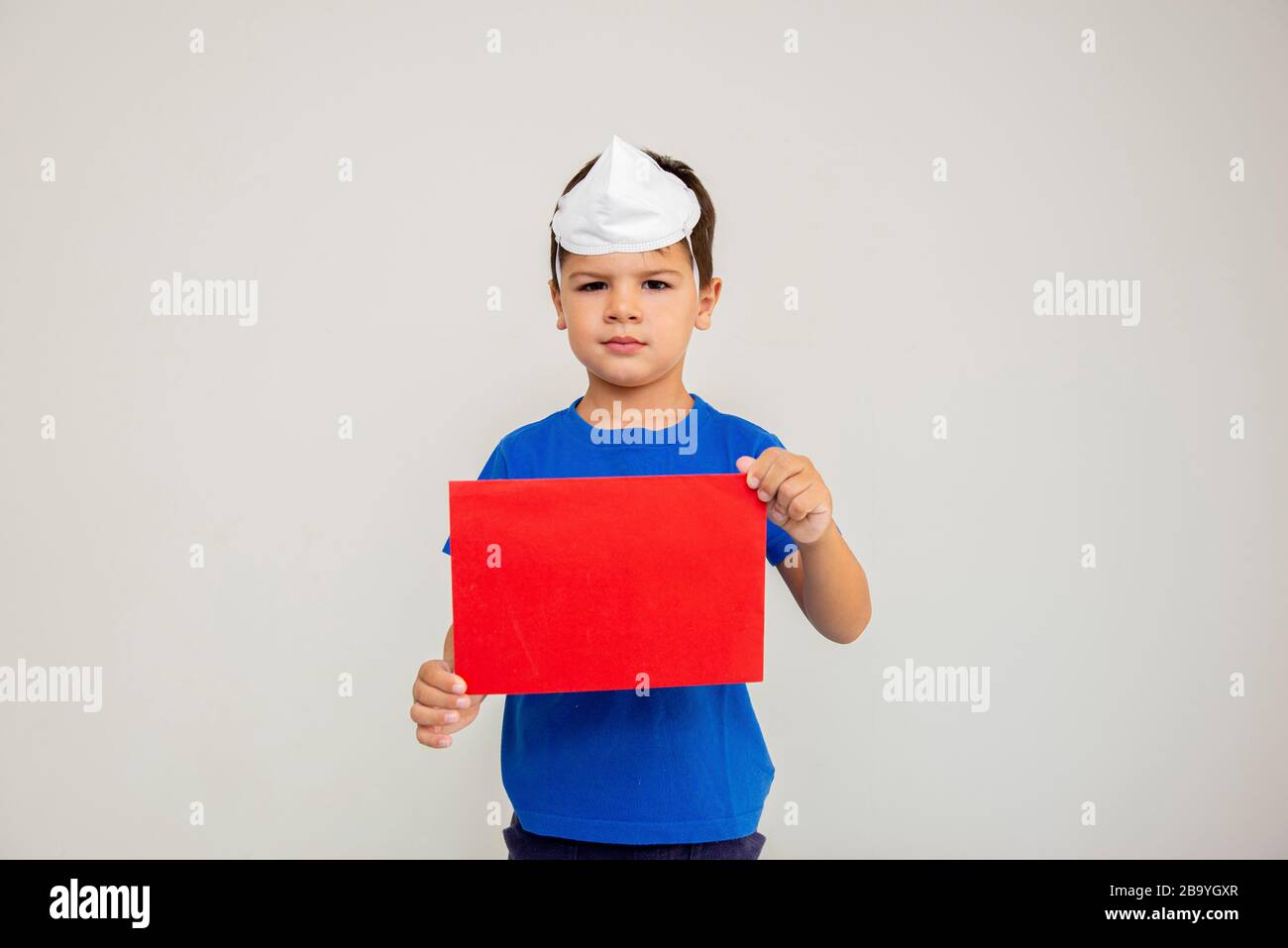 Caucasian boy with surgical mask on his head holding blank sheet. Face ...