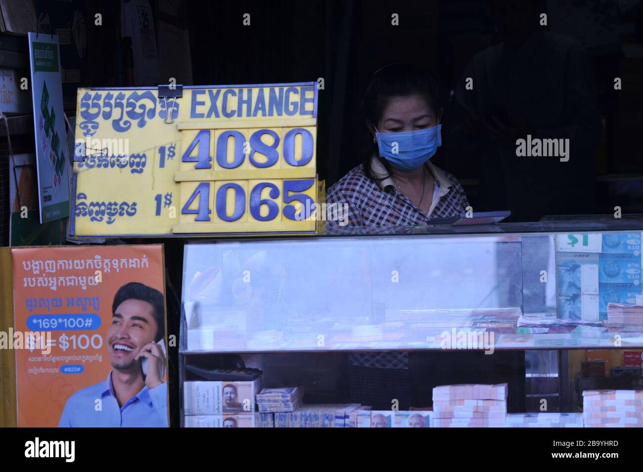 A Cambodian woman wearing a face mask at a money exchange booth during ...