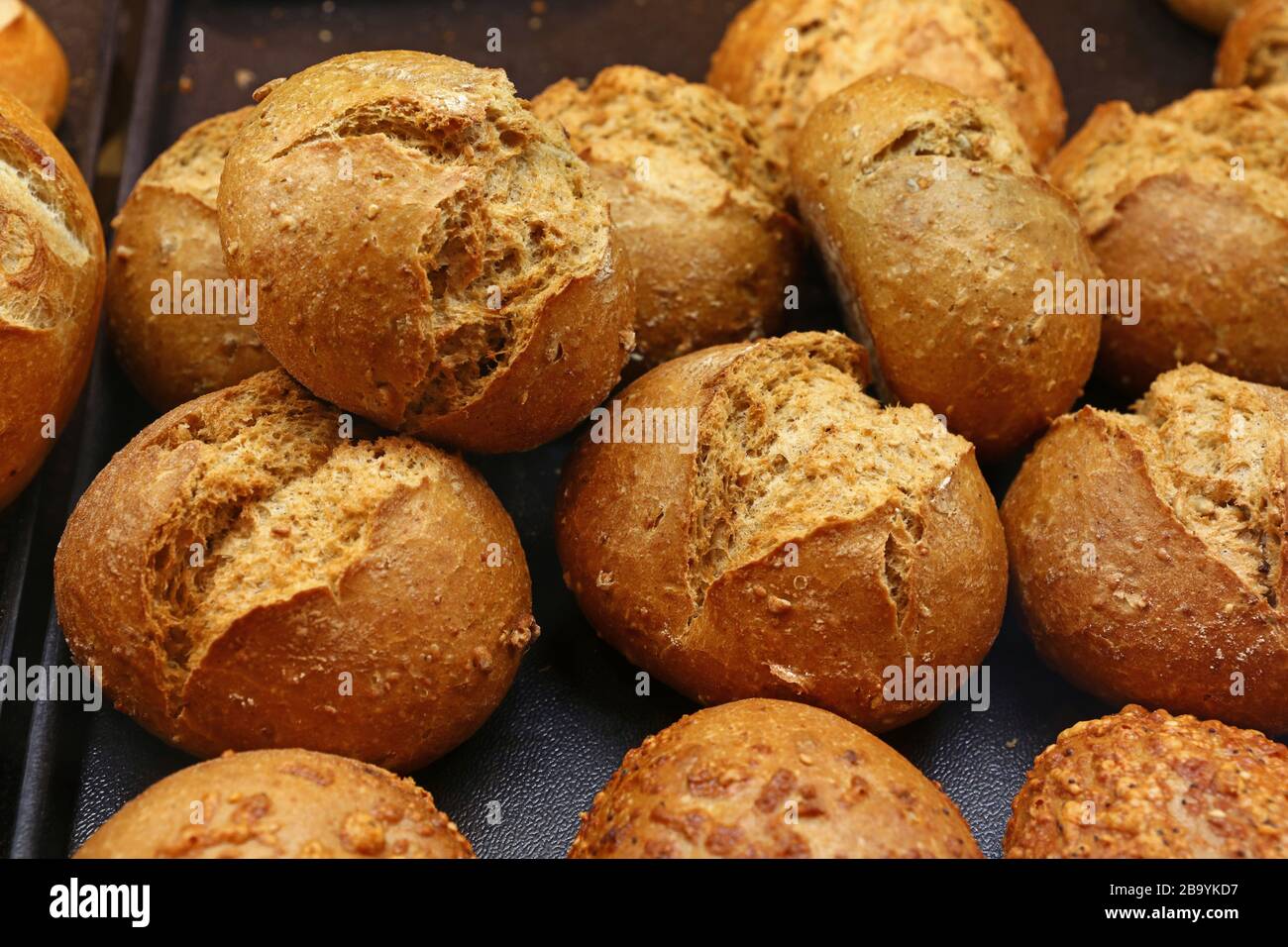 Close up several fresh wheat bread buns with seeds on retail display of ...