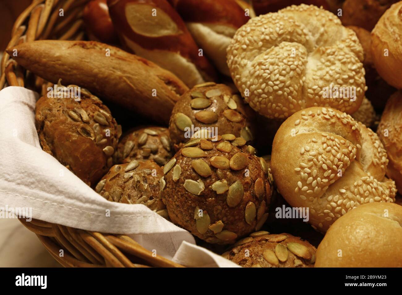 Close up several assorted fresh bread buns in basket on retail display ...