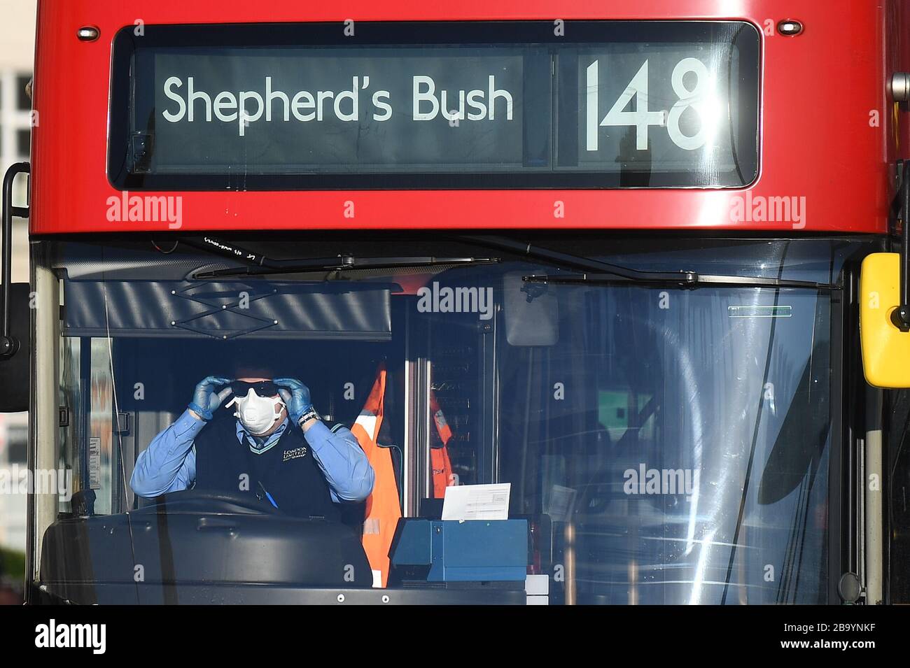 A London bus driver adjusts his sunglasses on Westminster Bridge ...