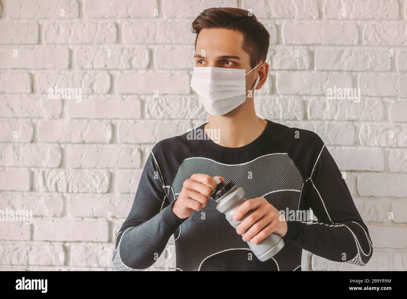 Young fitness man wearing medical face mask for personal protection and ...