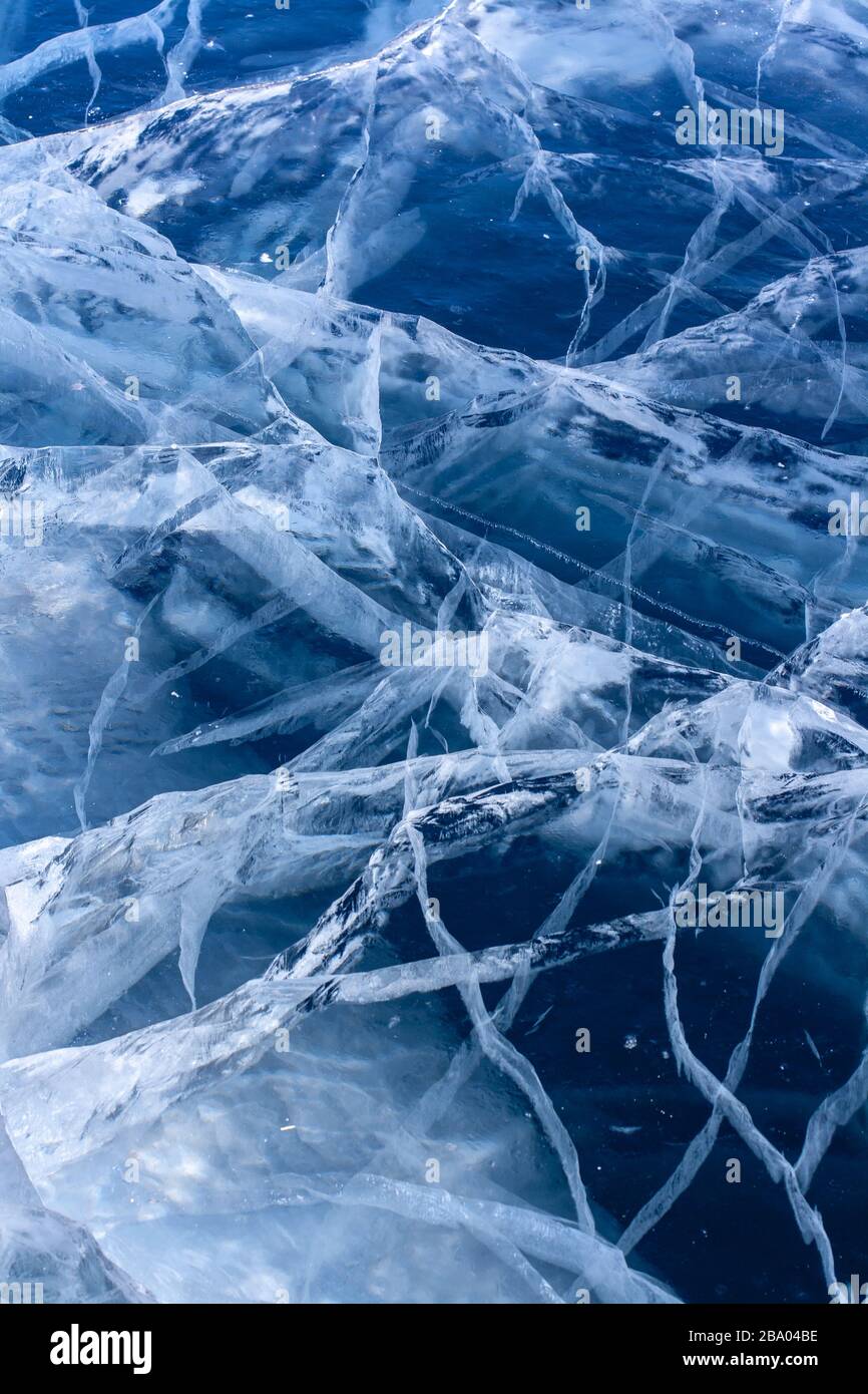 Natural texture of clear blue ice with deep cracks. Beautiful cracks in ...