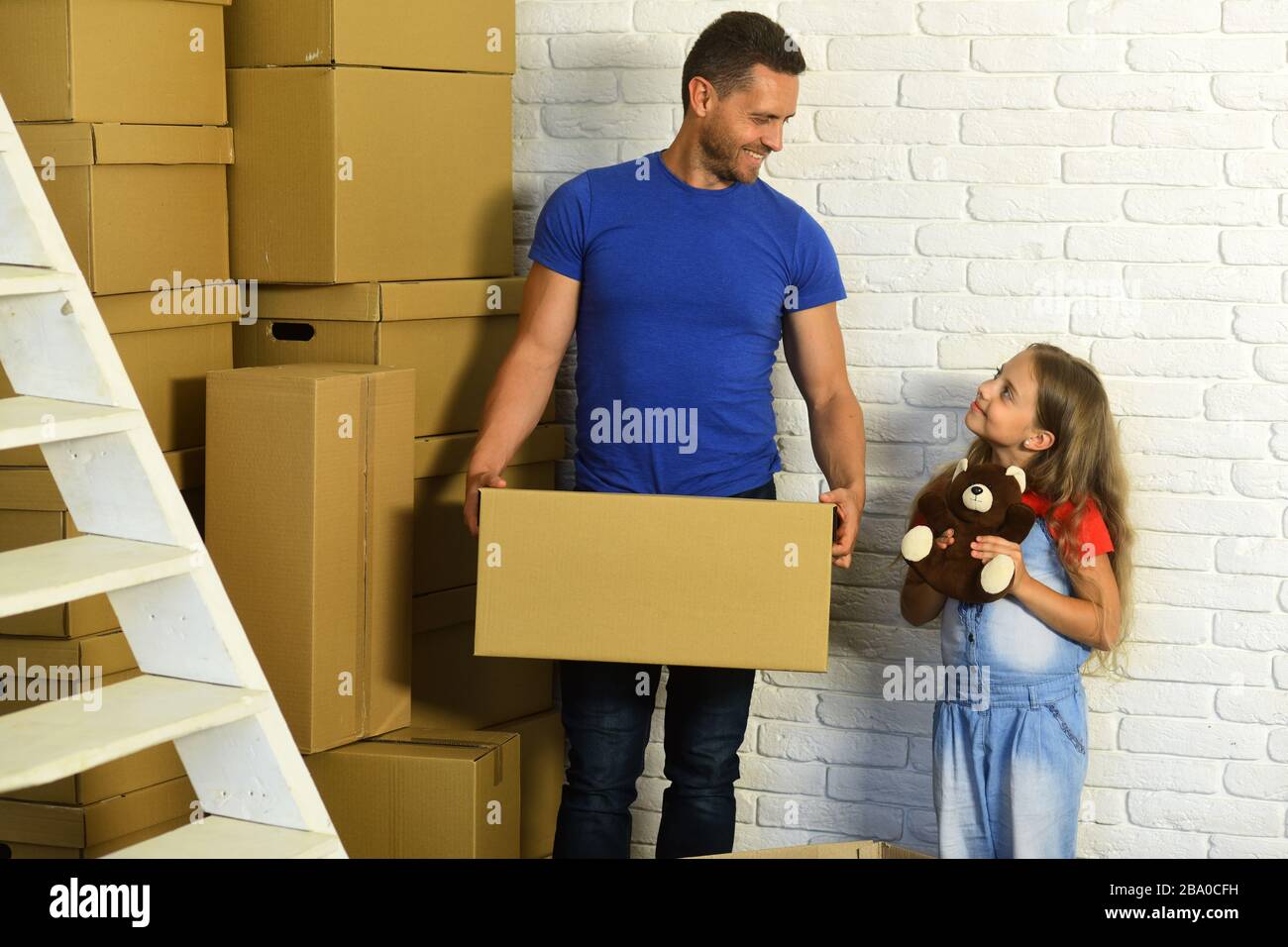 New home and family concept. Daughter and father hold box, brown teddy ...