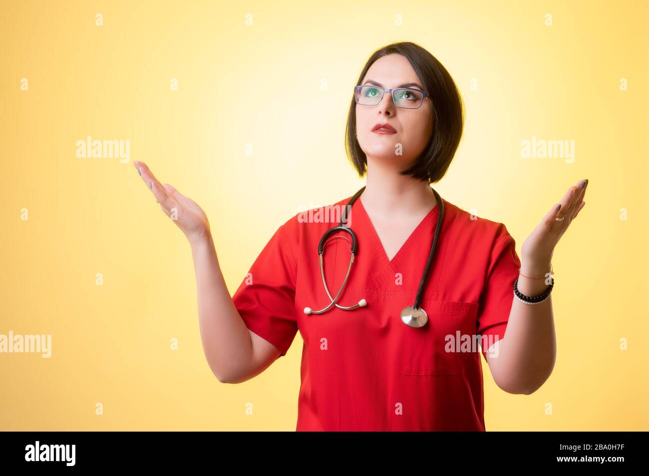 Portrait of beautiful woman doctor with stethoscope wearing red scrubs ...
