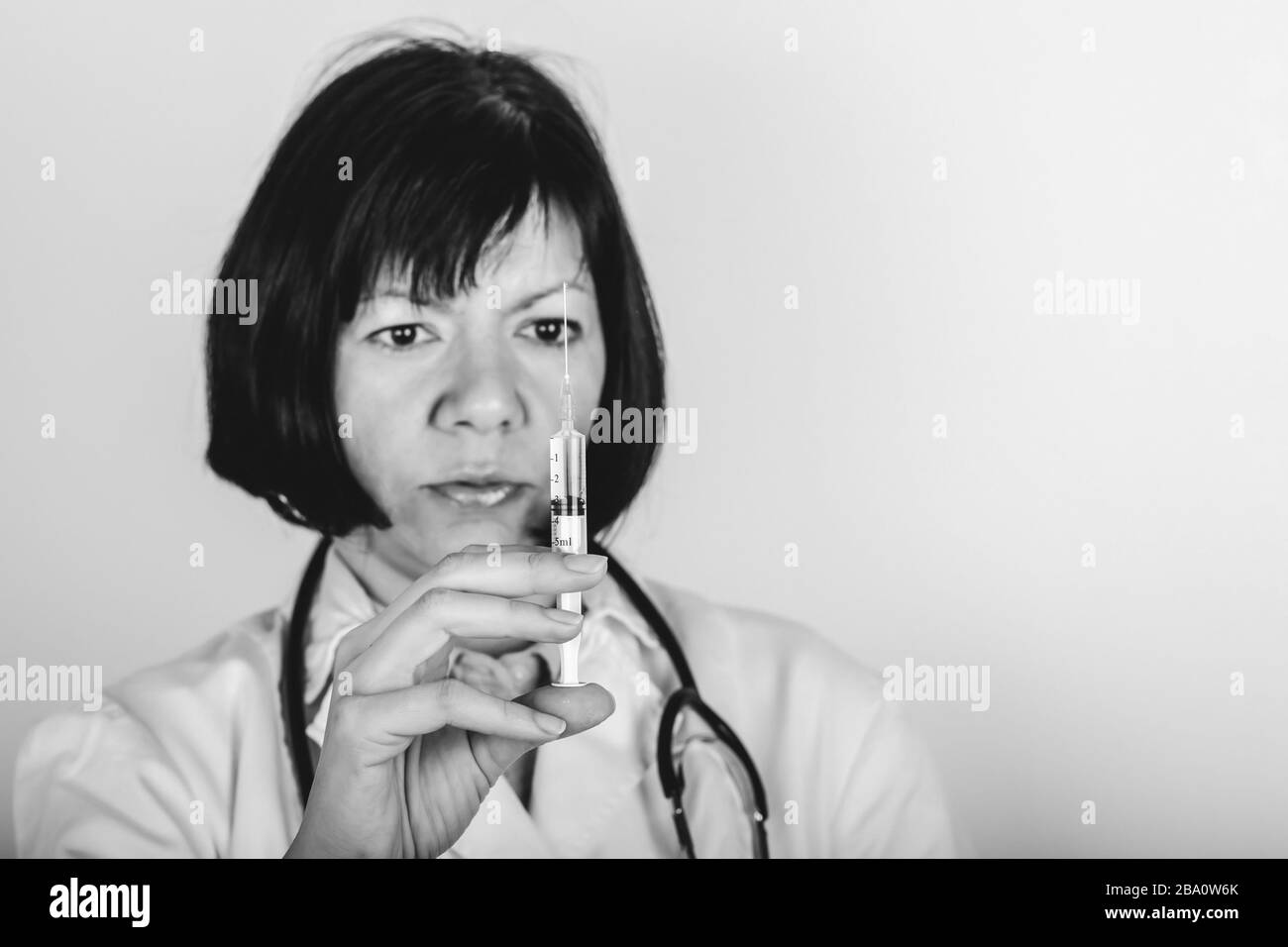 Female doctor in white lab coat on white background holds a syringe ...