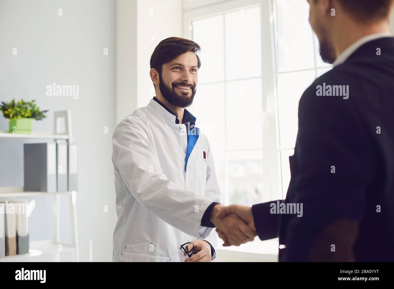 Handshake. Practicing doctor and patient shaking hands smiling at the ...